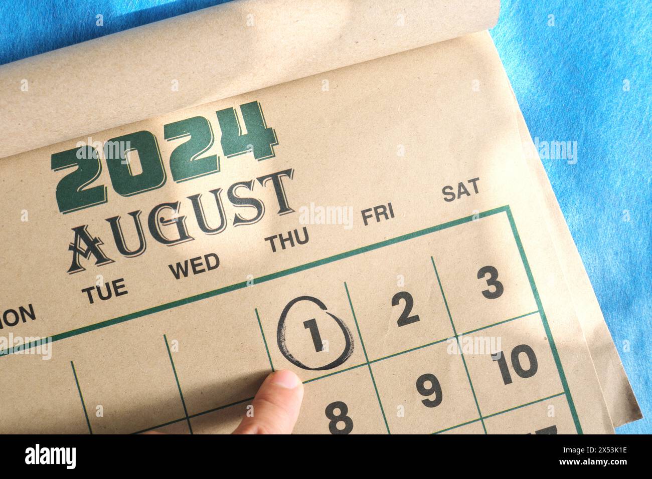 Hand pointing on August 1 2024 date on calendar flat lay in blue ...
