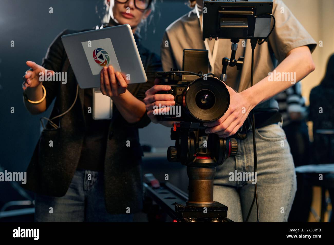 Font view cropped shot of two women operating pro video camera working ...