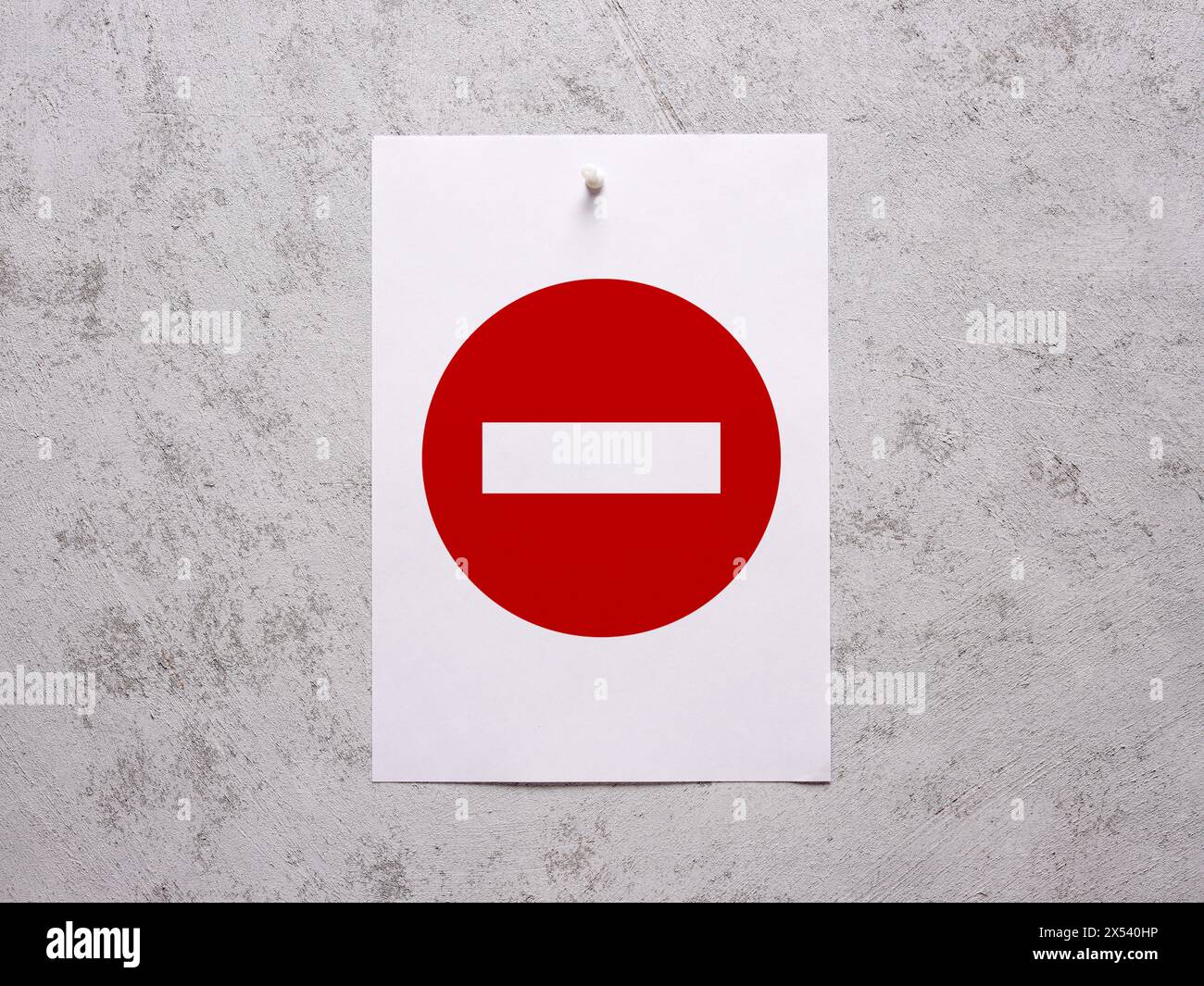 White sheet of paper with no entry sign pinned to a white concrete wall ...