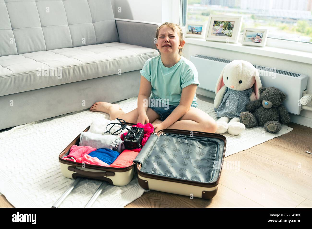 Little girl crying while unpacking her suitcase after vacation ...