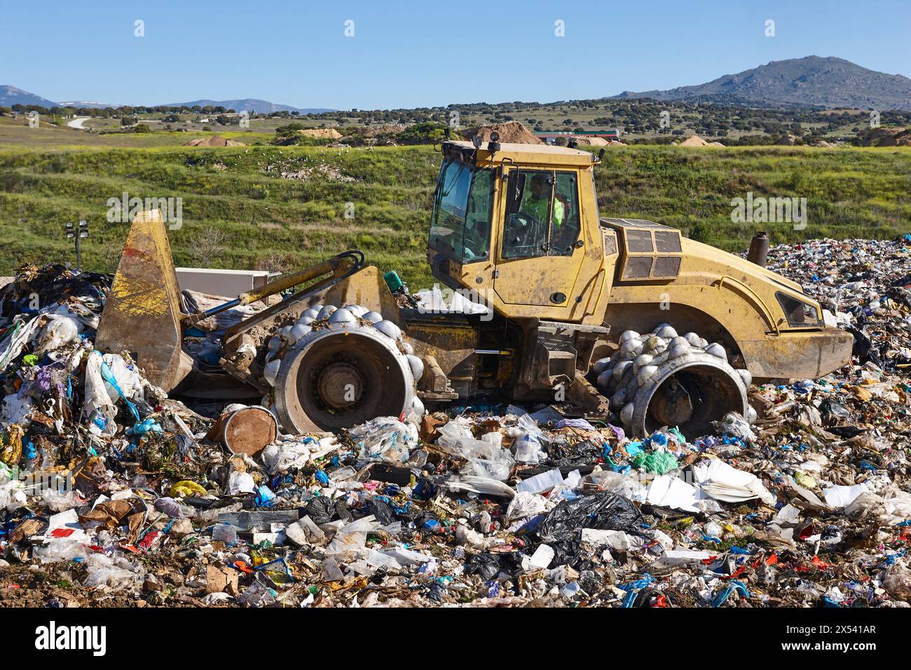 Heavy machinery shredding garbage in an open air landfill. Waste Stock ...