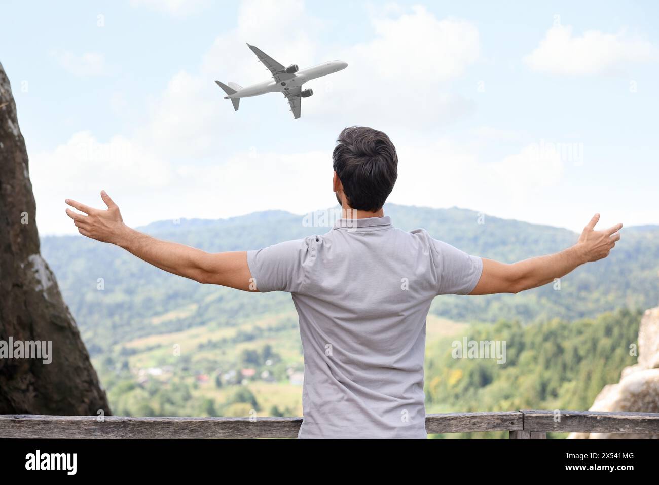 Man looking at airplane flying in sky over mountains, back view Stock ...