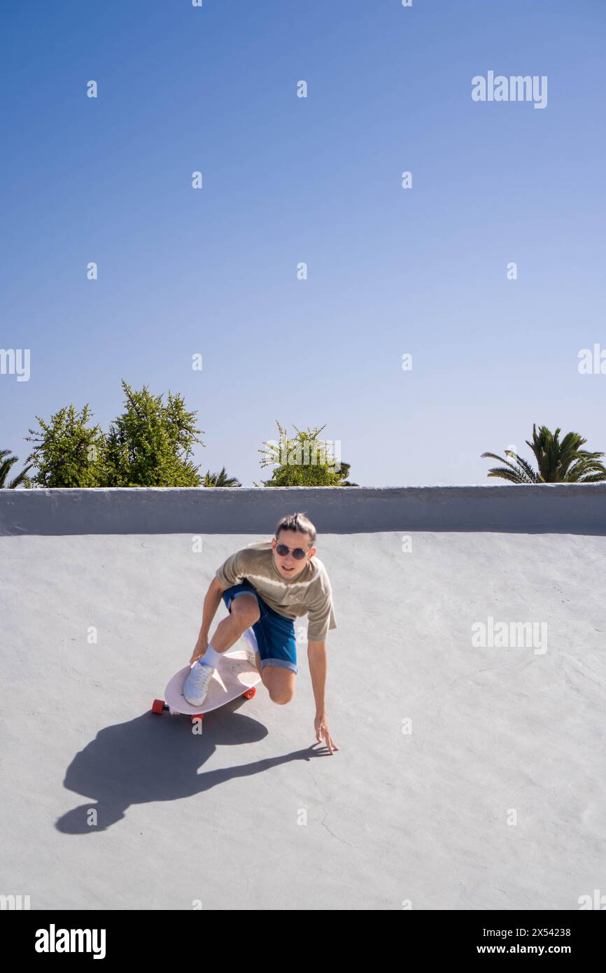 A woman is skillfully standing on a skateboard on a ramp, demonstrating ...