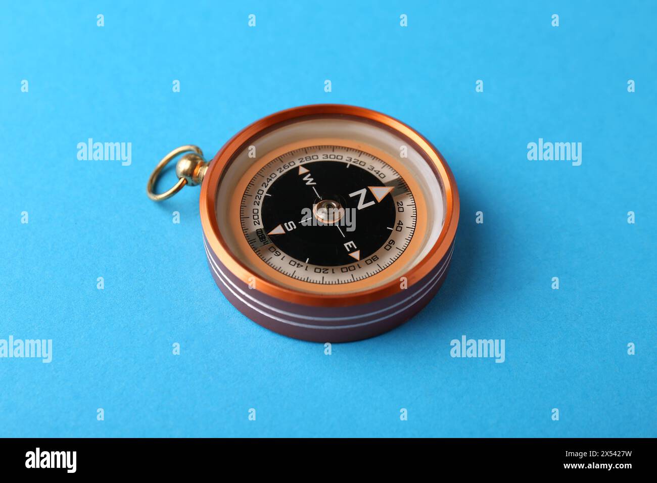 One compass on light blue background. Tourist equipment Stock Photo - Alamy