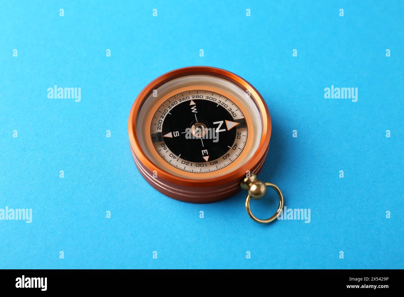 One compass on light blue background. Tourist equipment Stock Photo - Alamy