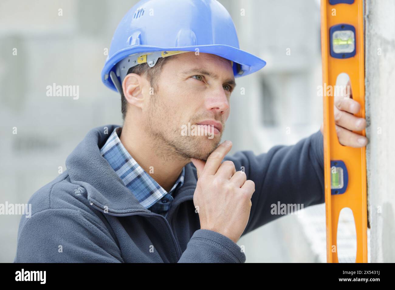 male builder thinking about level wall Stock Photo - Alamy