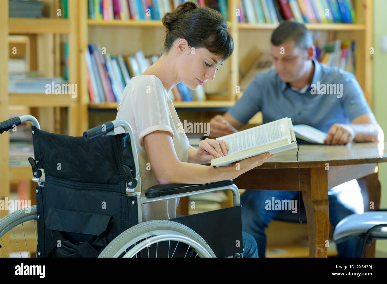 disabled woman in wheelchair reading book in library Stock Photo - Alamy