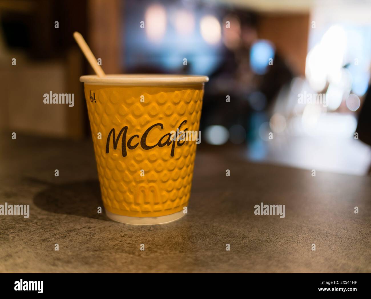 Yellow paper branded McCafe coffee cup with wooden stir stick on stone ...