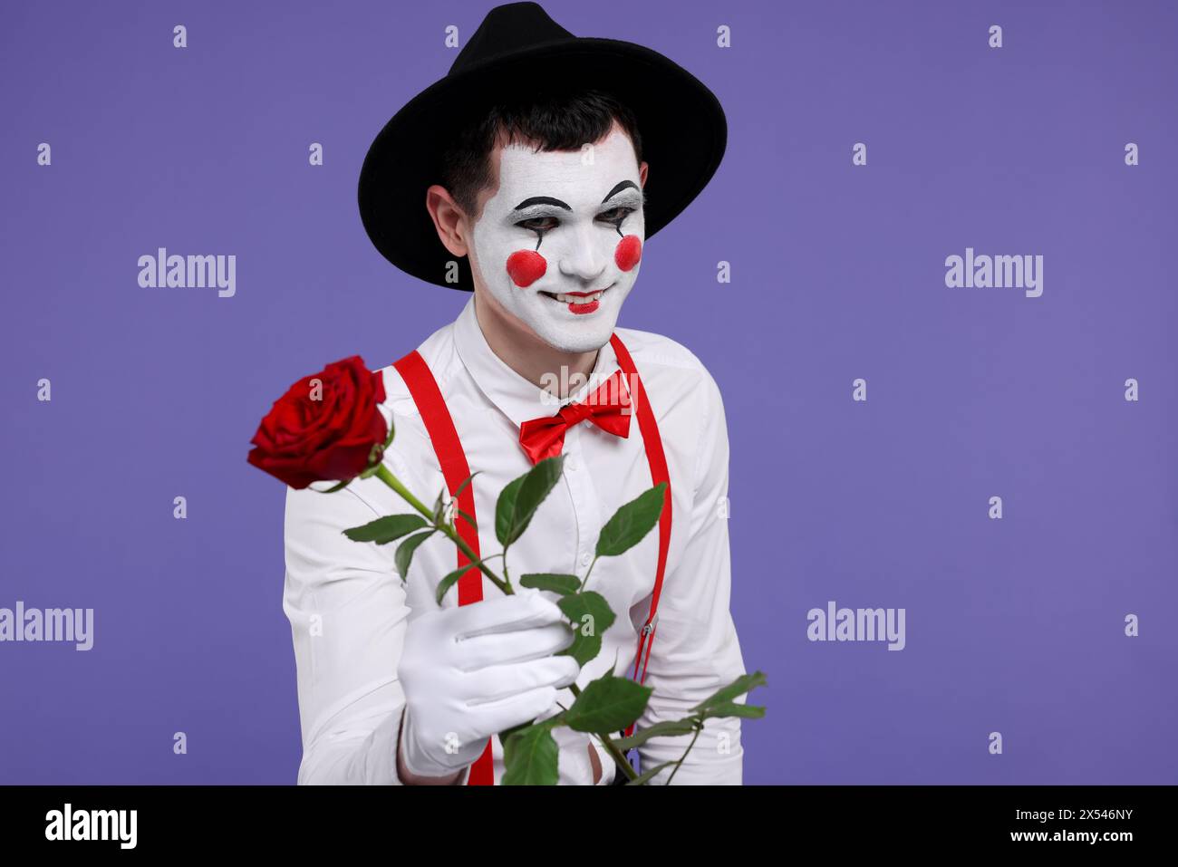 Funny mime artist with red rose on purple background Stock Photo - Alamy