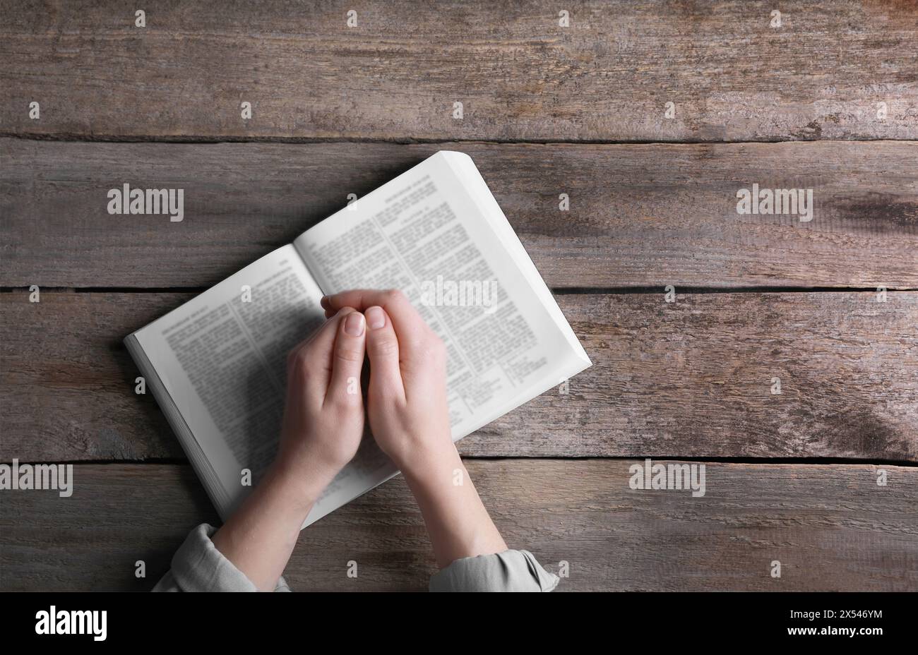 Religion. Christian woman praying over Bible at wooden table, top view ...