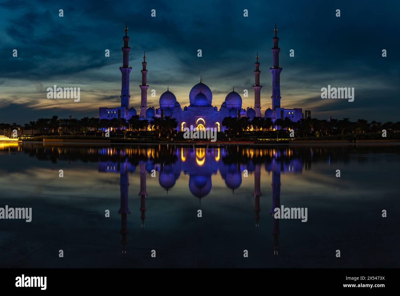 A picture of the illuminated Sheikh Zayed Grand Mosque reflected on the ...