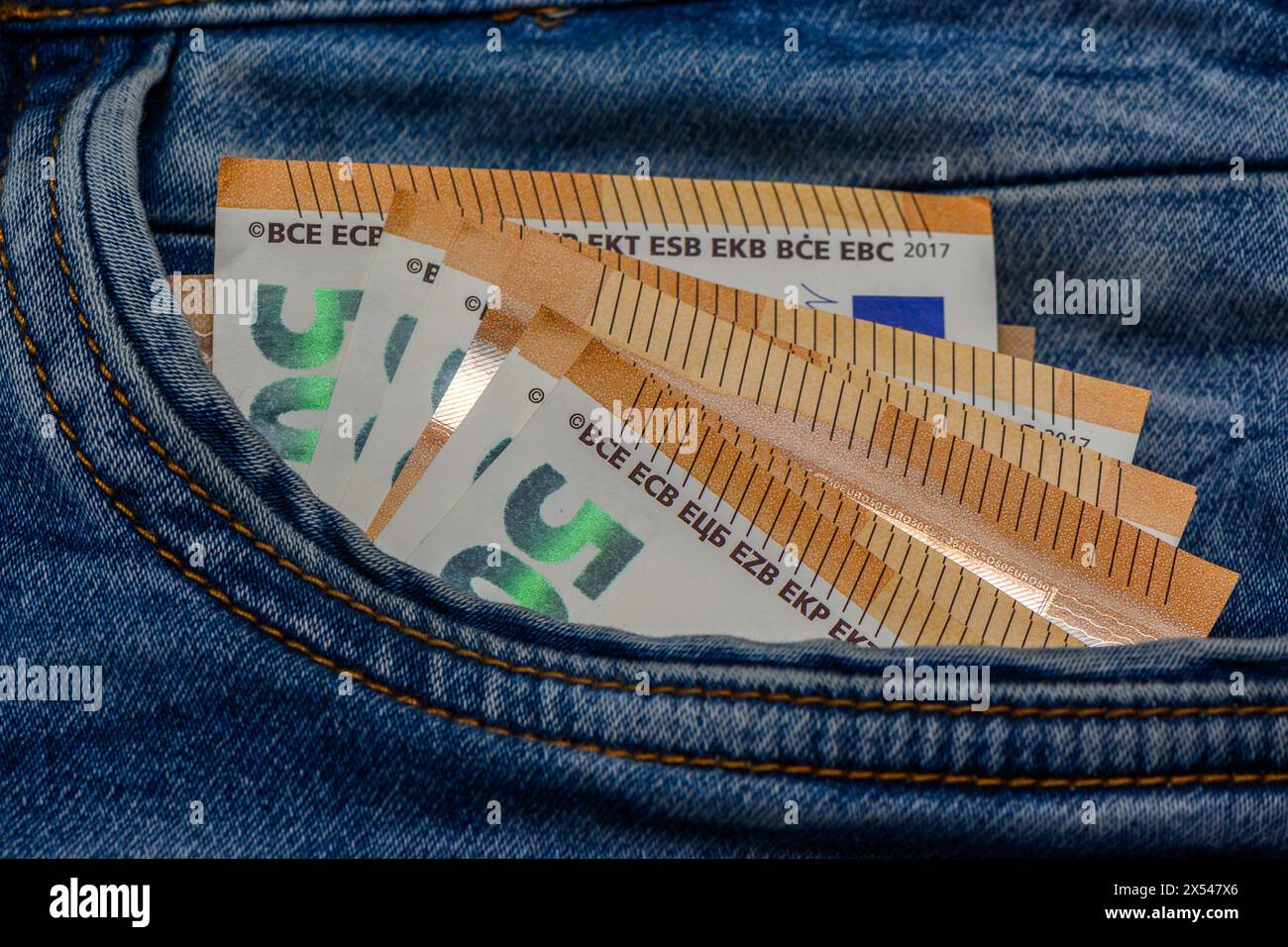 Three folded 50 Euro banknote bills stuck in front pocket of blue jeans ...