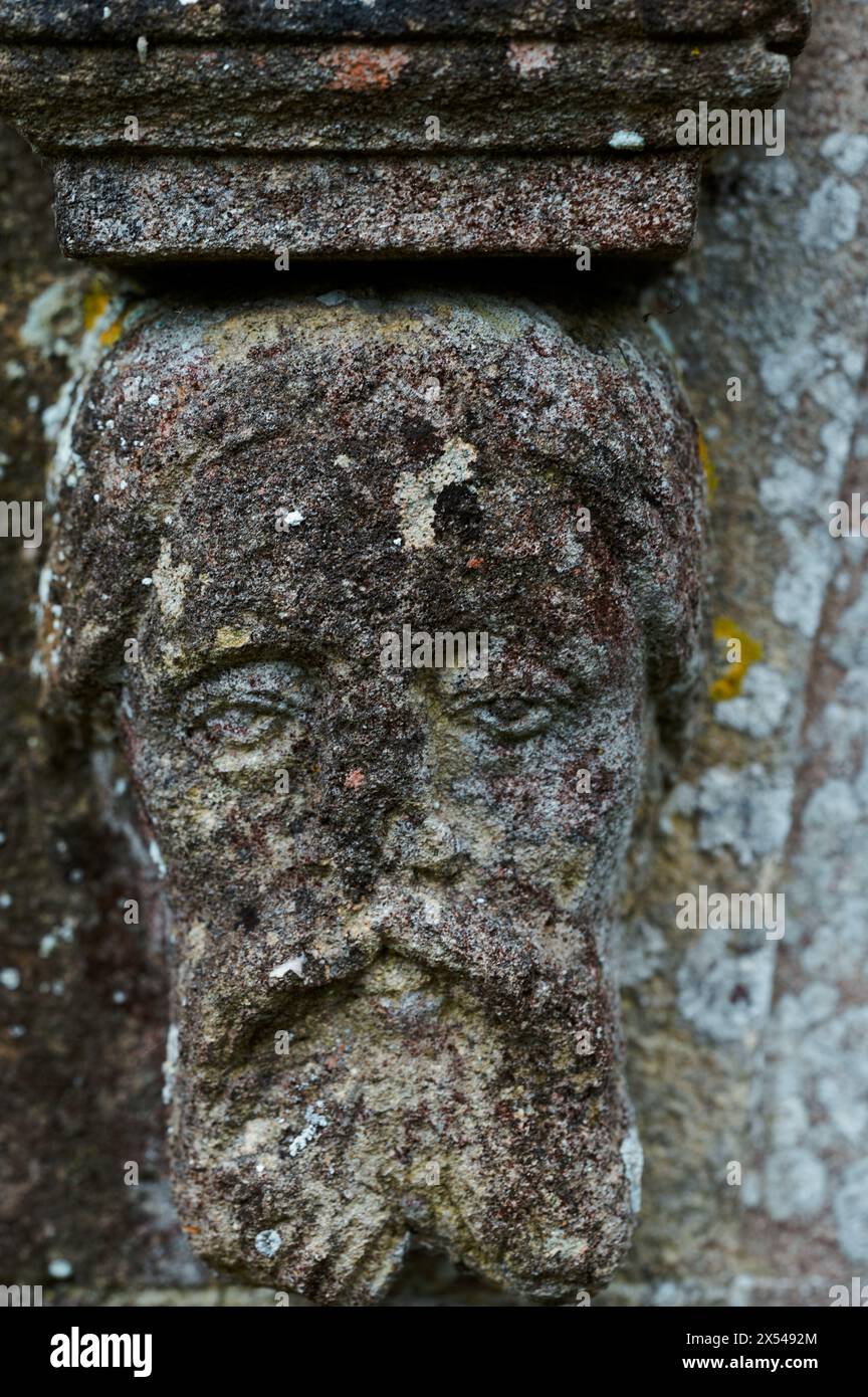 Close-up of a weathered stone corbel head at the base of a church door ...