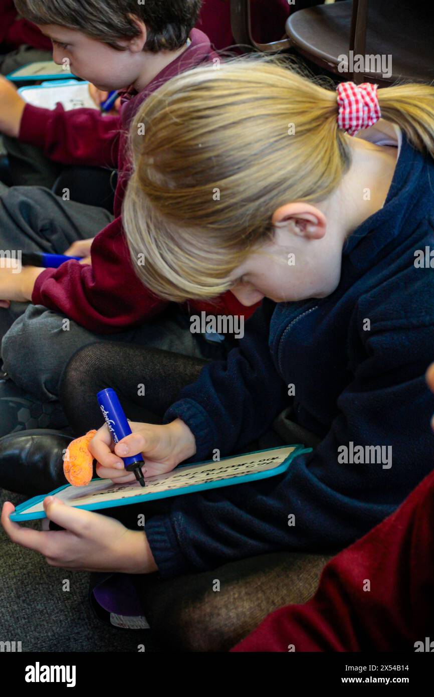 Primary school children writing on a wipe clean slate during a lesson ...
