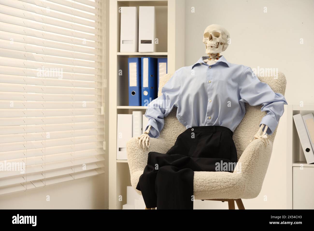 Waiting concept. Human skeleton sitting in armchair at office, space ...