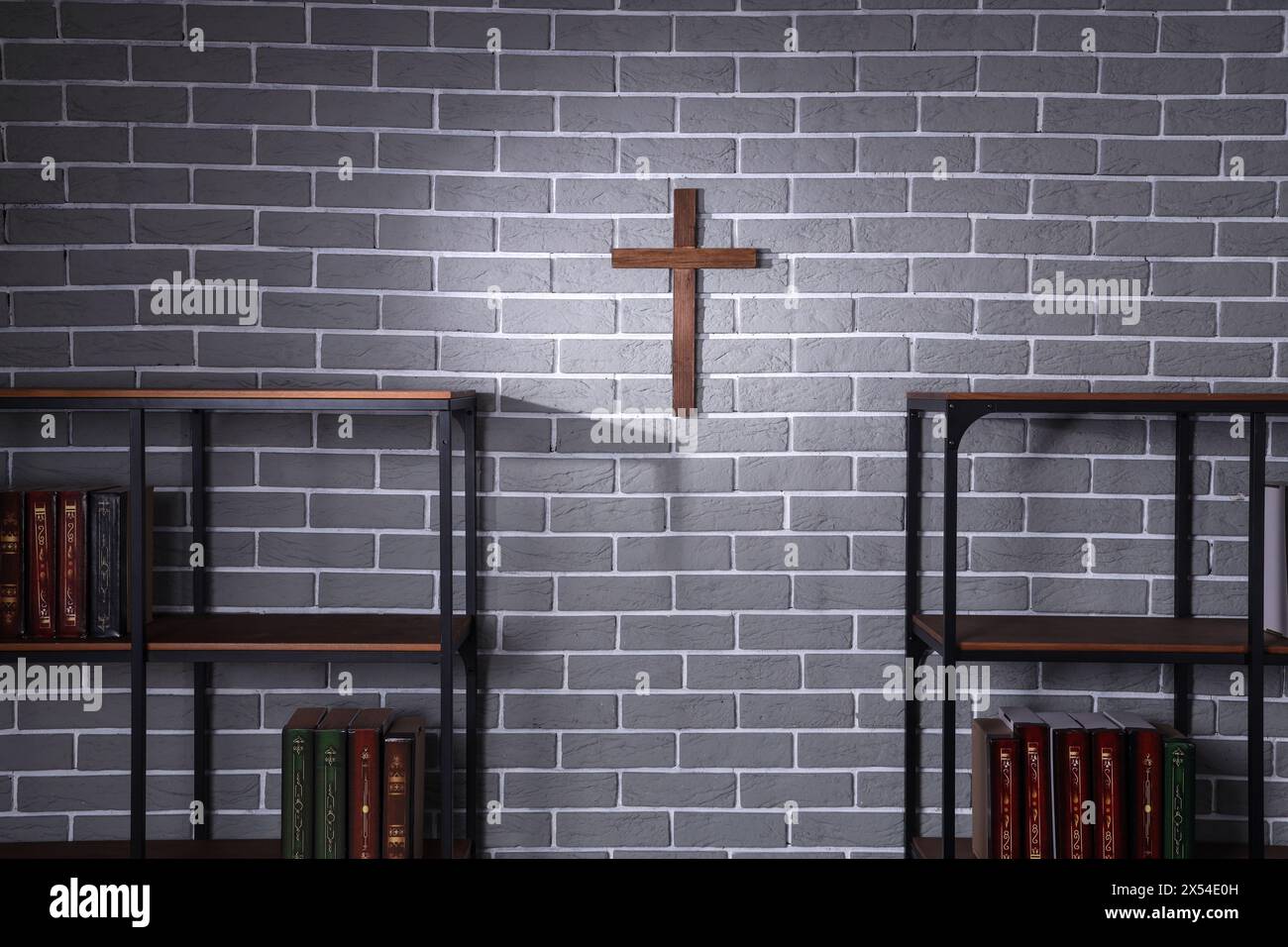 Wooden cross hanging on grey brick wall in room Stock Photo - Alamy