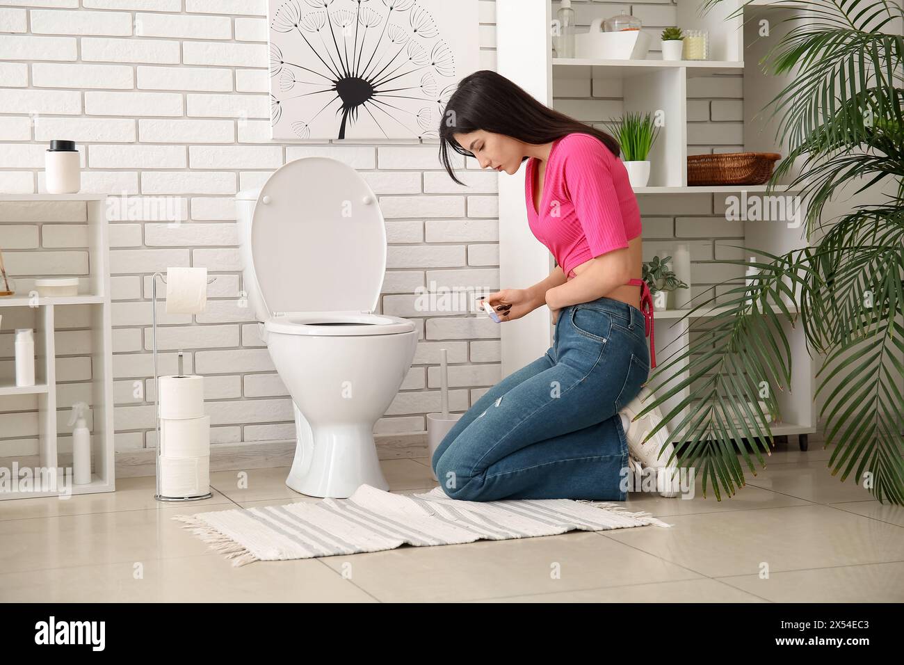 Sick young woman with pregnancy test near toilet bowl in restroom Stock ...