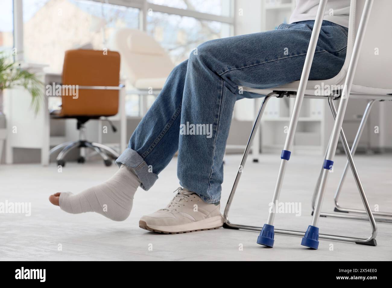 Injured young man after accident with crutches sitting in clinic Stock ...