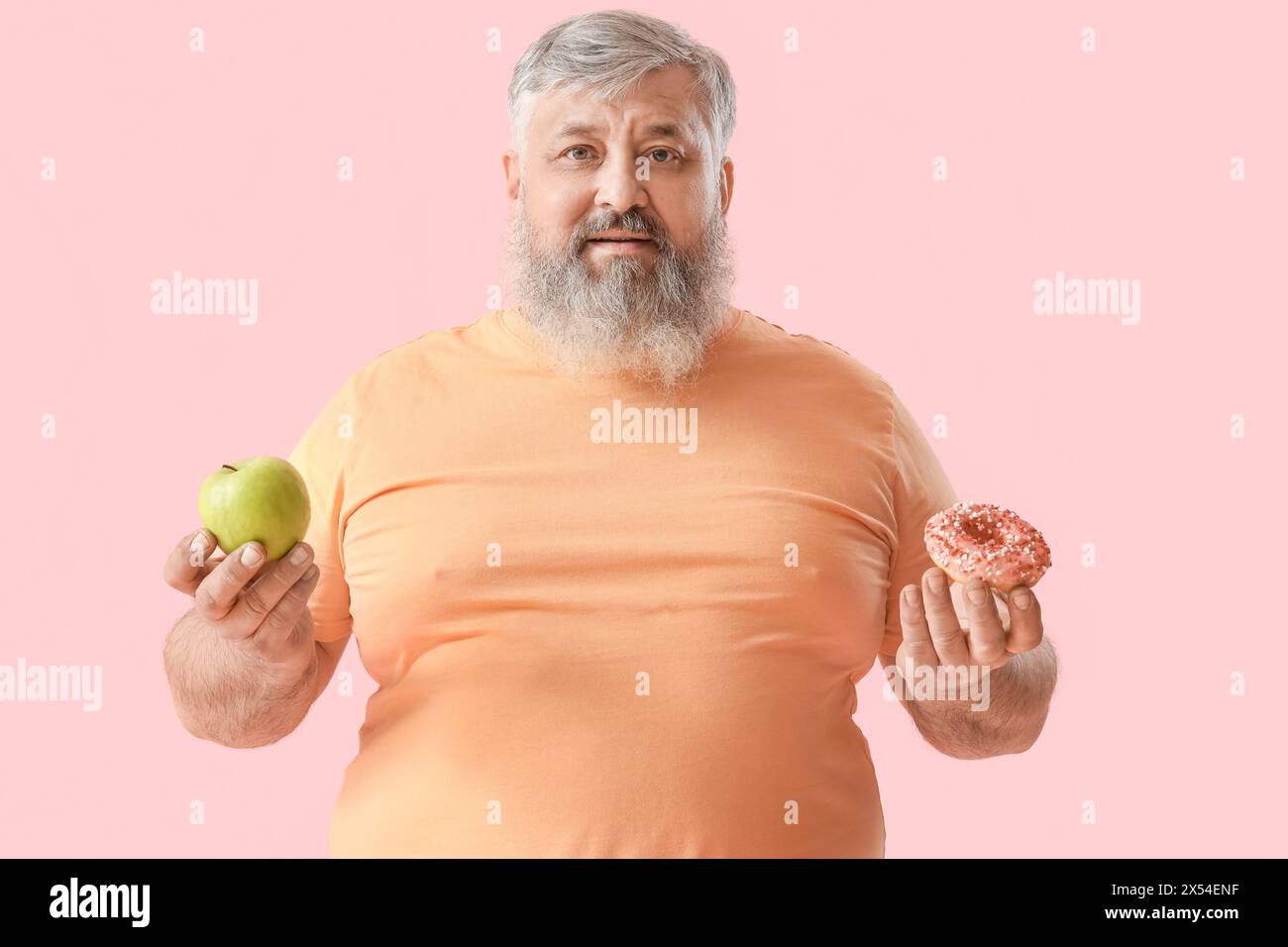 Overweight happy mature man with apple and donut on pink background ...