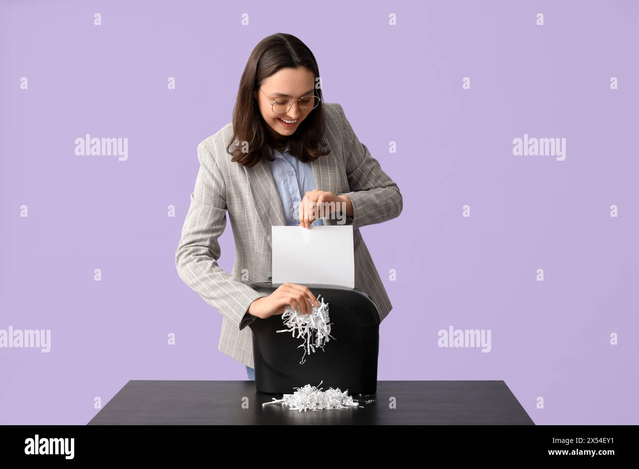 Secretary destroying document in shredder on lilac background Stock ...