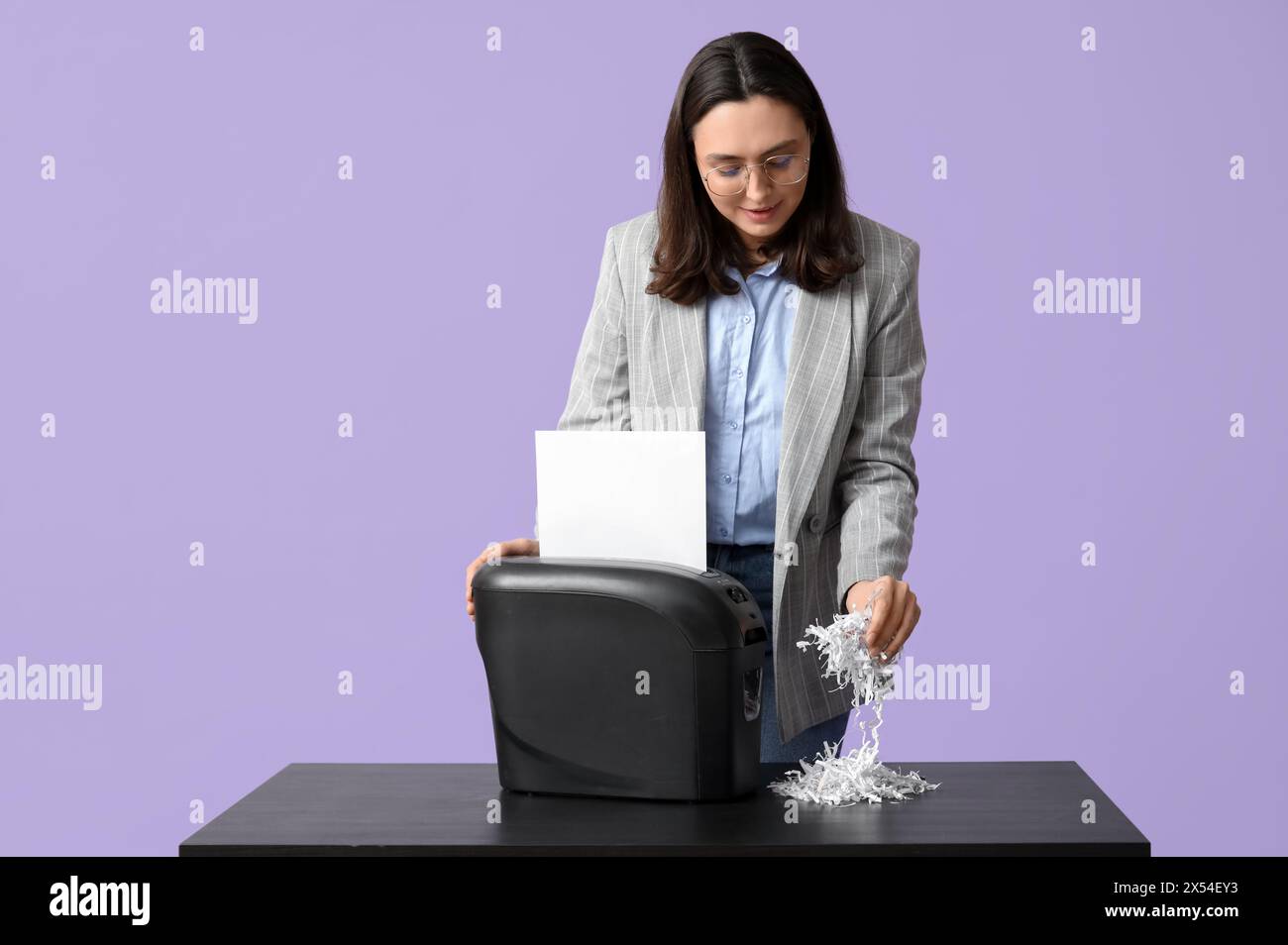 Secretary destroying document in shredder on lilac background Stock ...