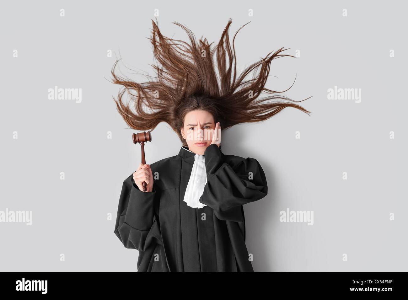 Serious young female judge with gavel lying on white background Stock ...