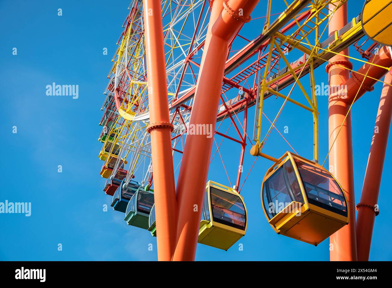 Ferris Wheel Over Blue Sky. Multicolored booths of a Ferris wheel over ...