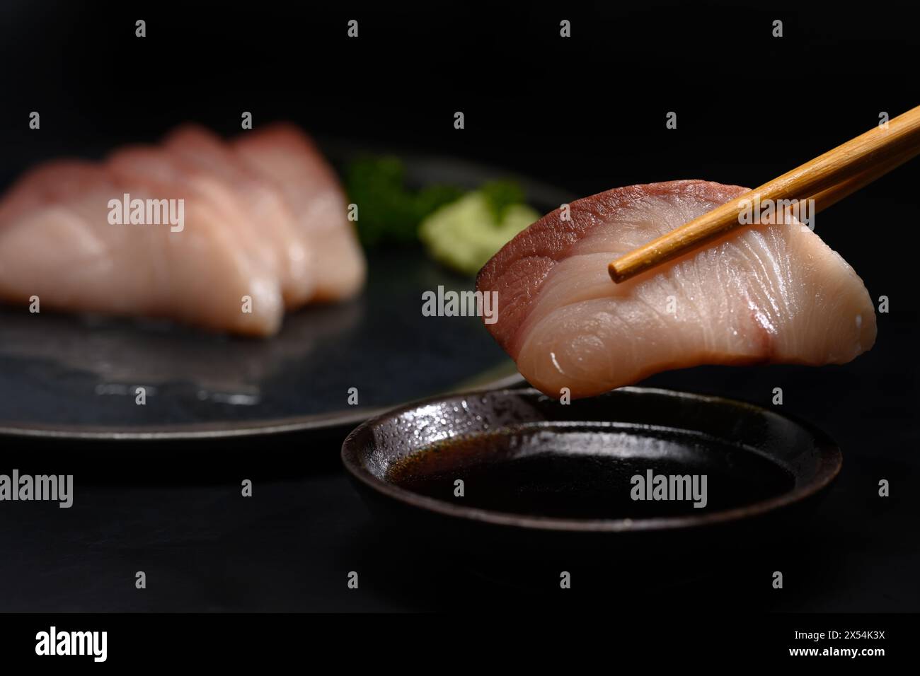Closeup chopsticks with Yellow tail fish or Hamachi Sashimi dipping ...