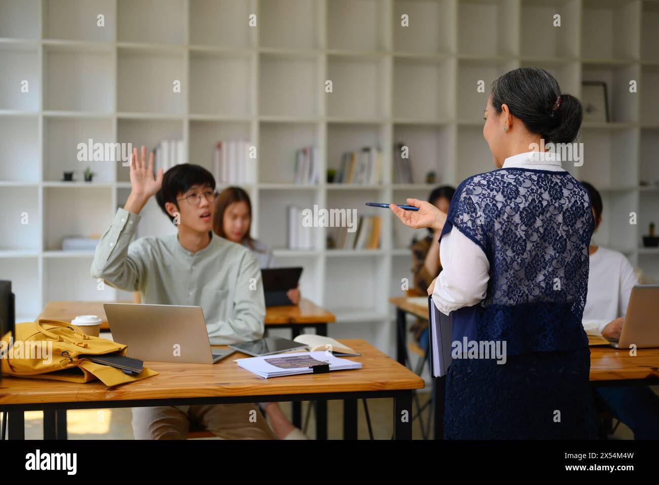 College student man raising his hand to answer question or ask ...