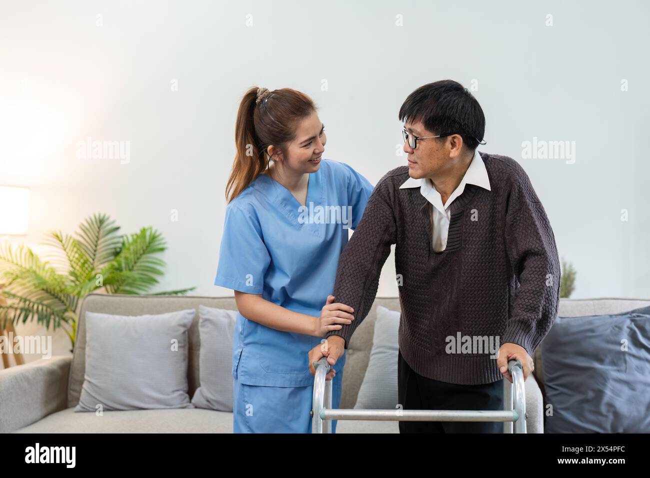 Nurse or caregiver help elderly walk by using walker at home ...