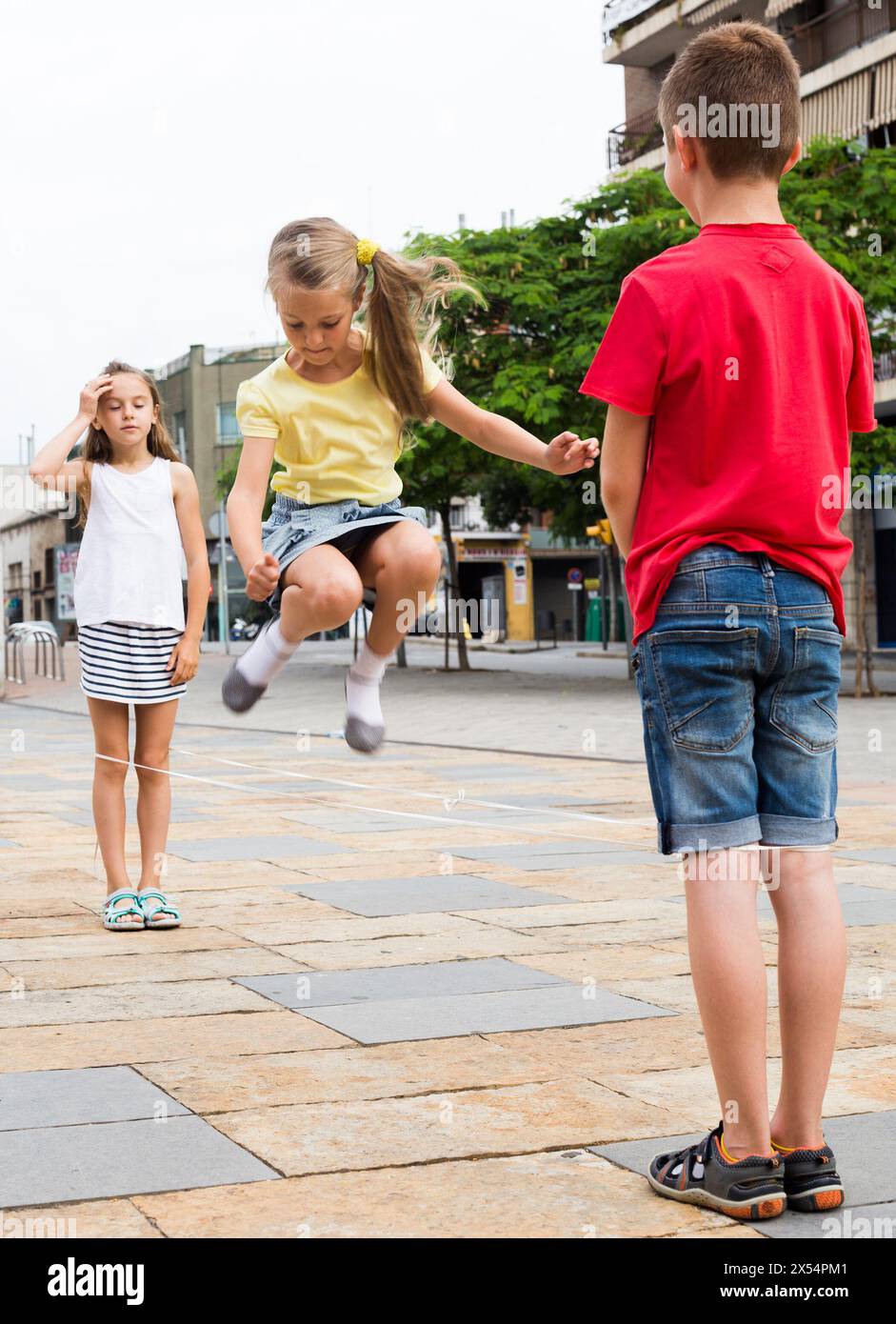 Blonde Girl jumps over rope on the sidewalk in the city in summer Stock ...
