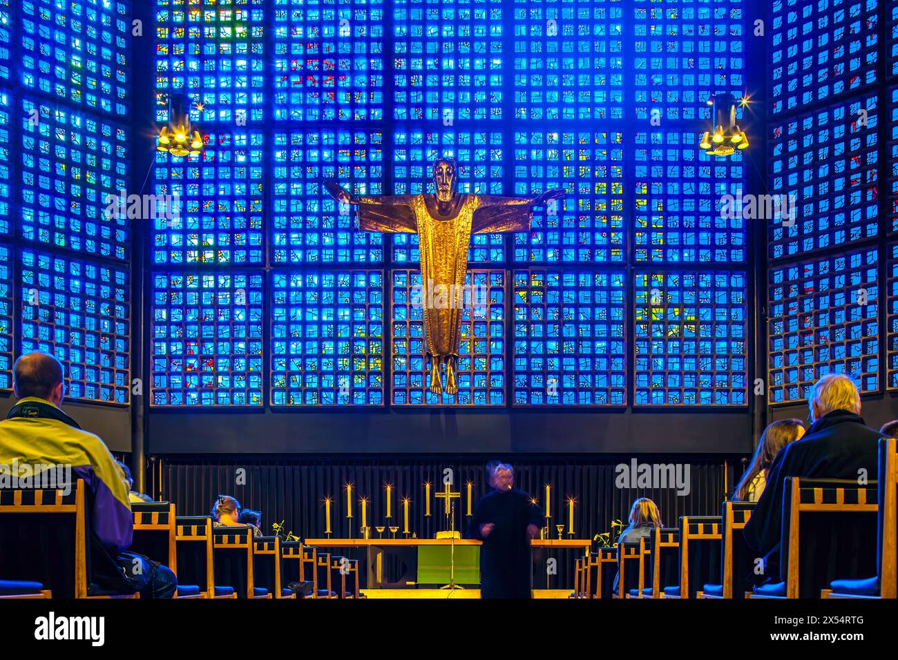 Congregants sit in peaceful reflection before the illuminated crucifix ...