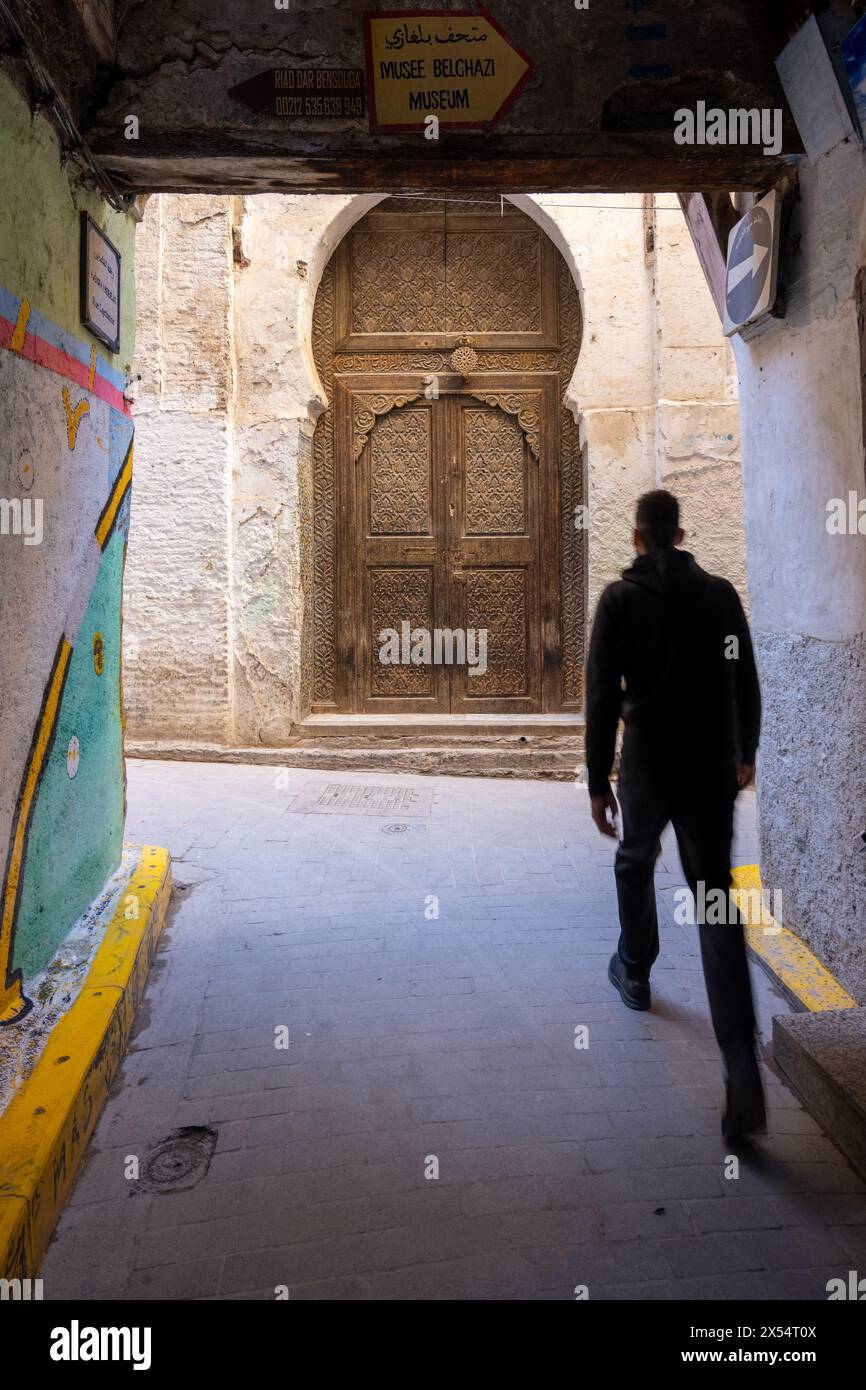 A young man walking down a narrow alleyway in the maze-like streets of ...
