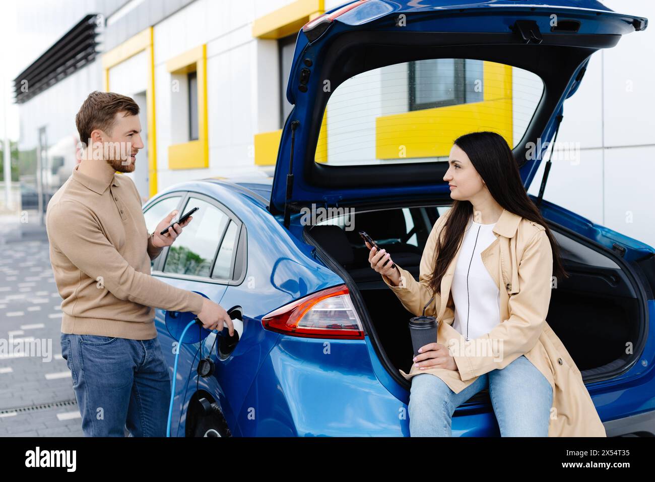 Young couple man and woman traveling by electric car having stop at ...