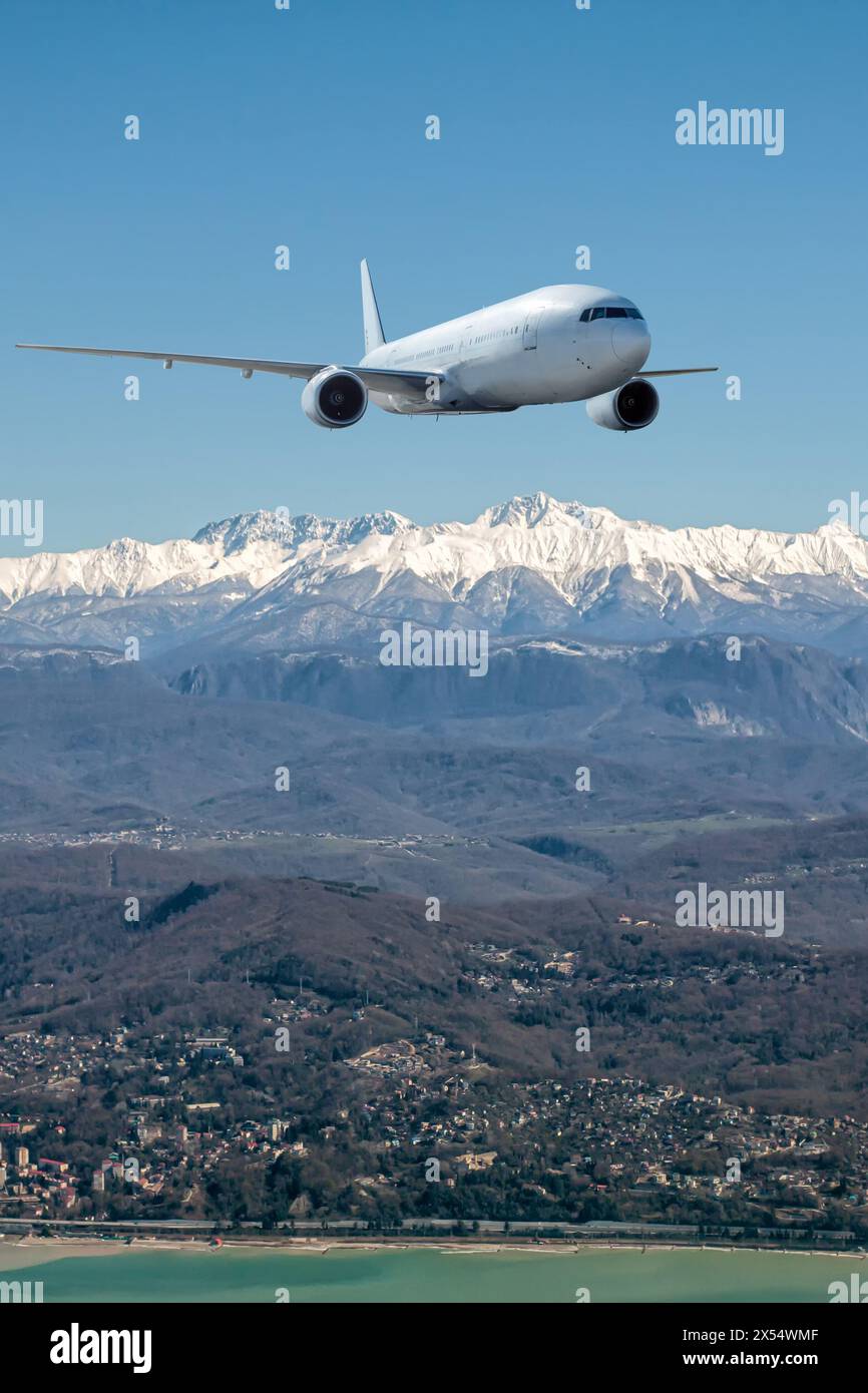 A white wide body passenger airplane flies over resort mountain town on ...