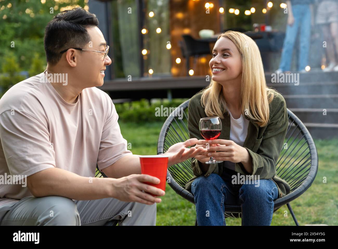 Diverse friends sitting together on backyard with drinks enjoying ...
