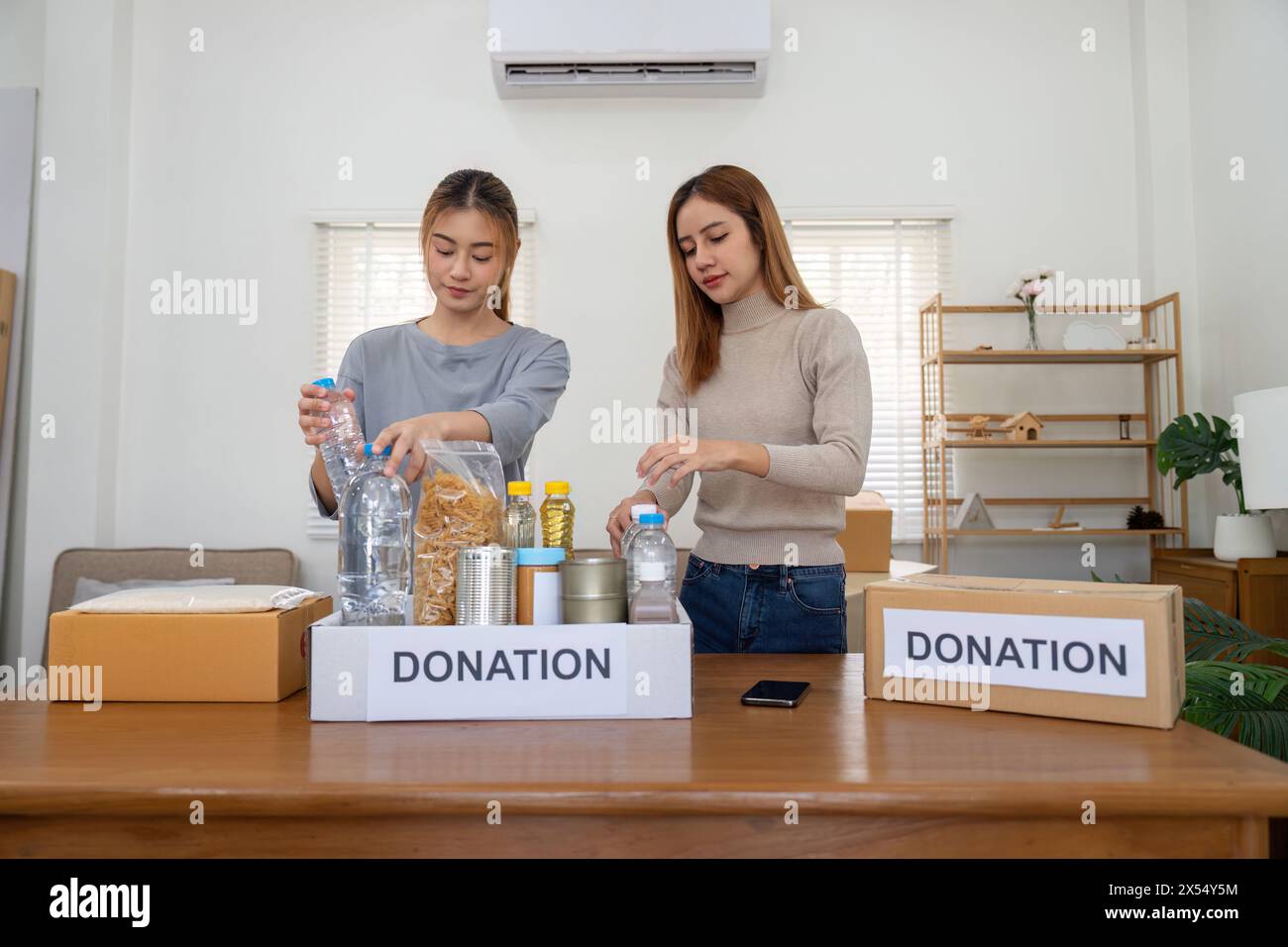 Happy young woman volunteer collecting, sorting food for needy people ...