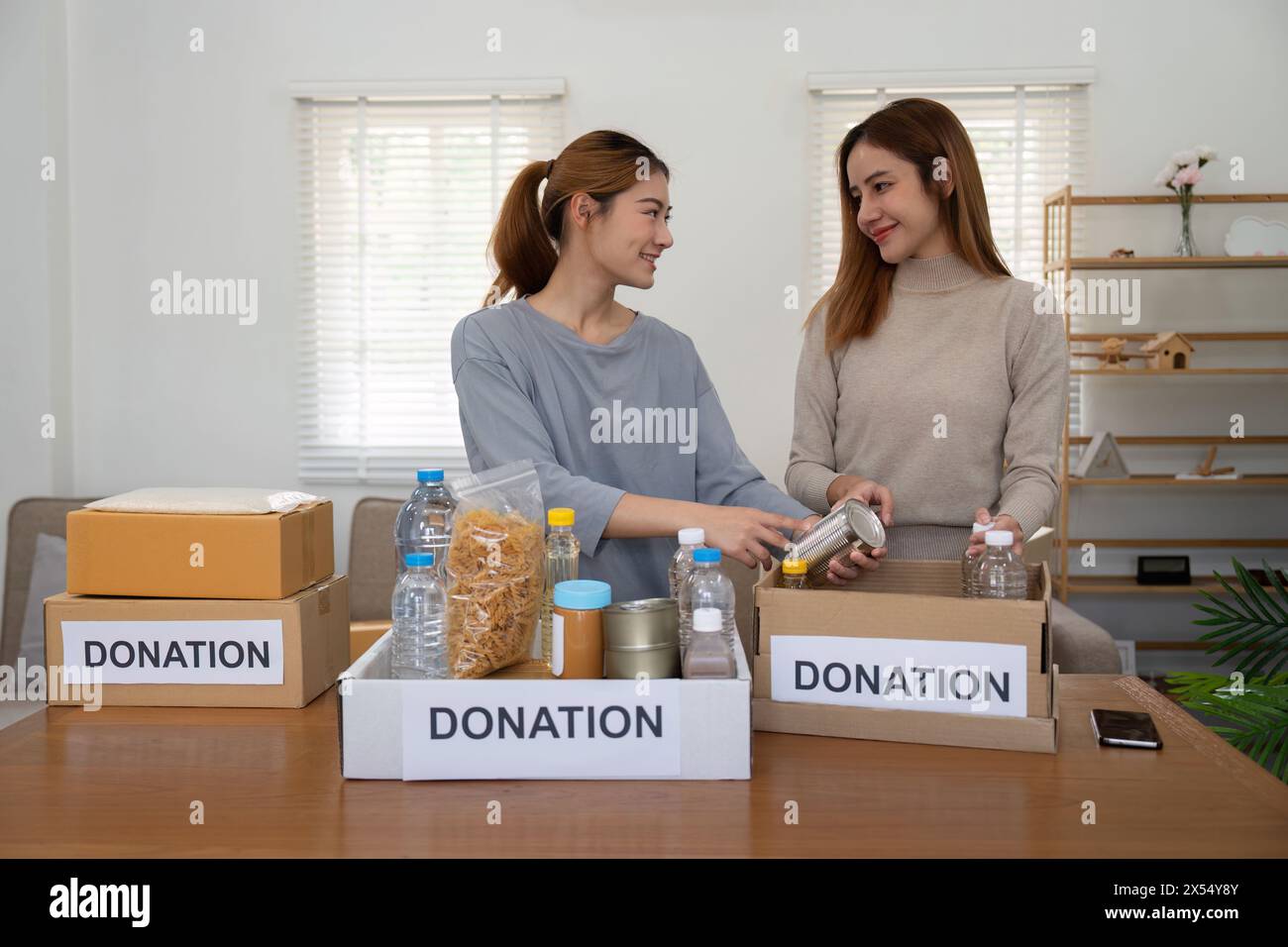 Happy young woman volunteer collecting, sorting food for needy people ...
