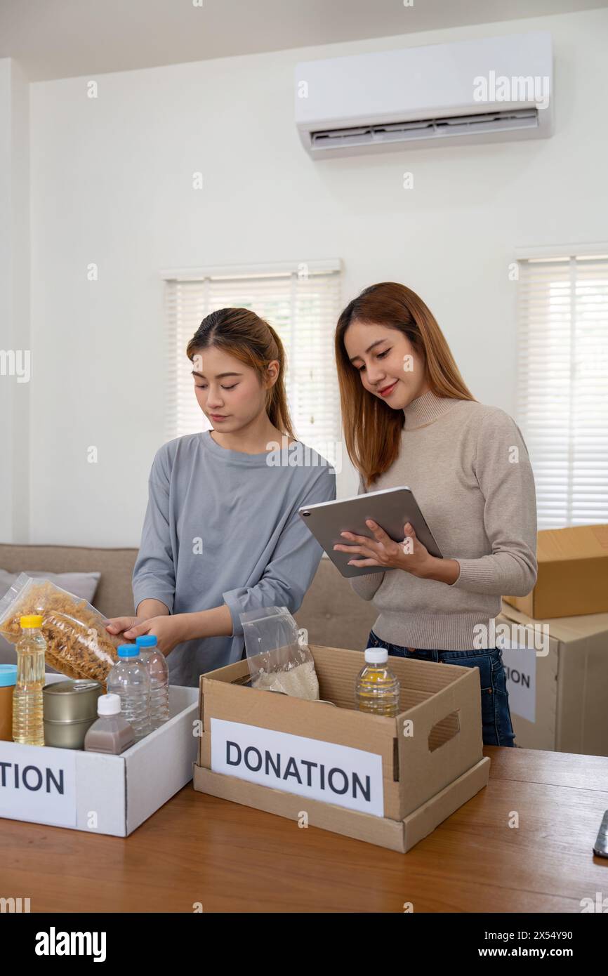 Happy young woman volunteer collecting, sorting food for needy people ...