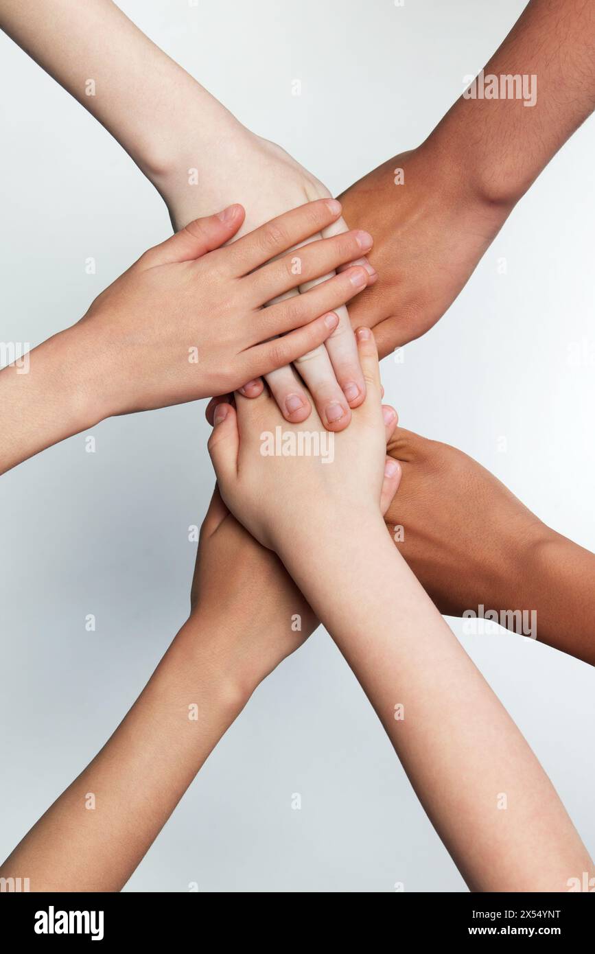 Close up of children putting their hands together against grey ...