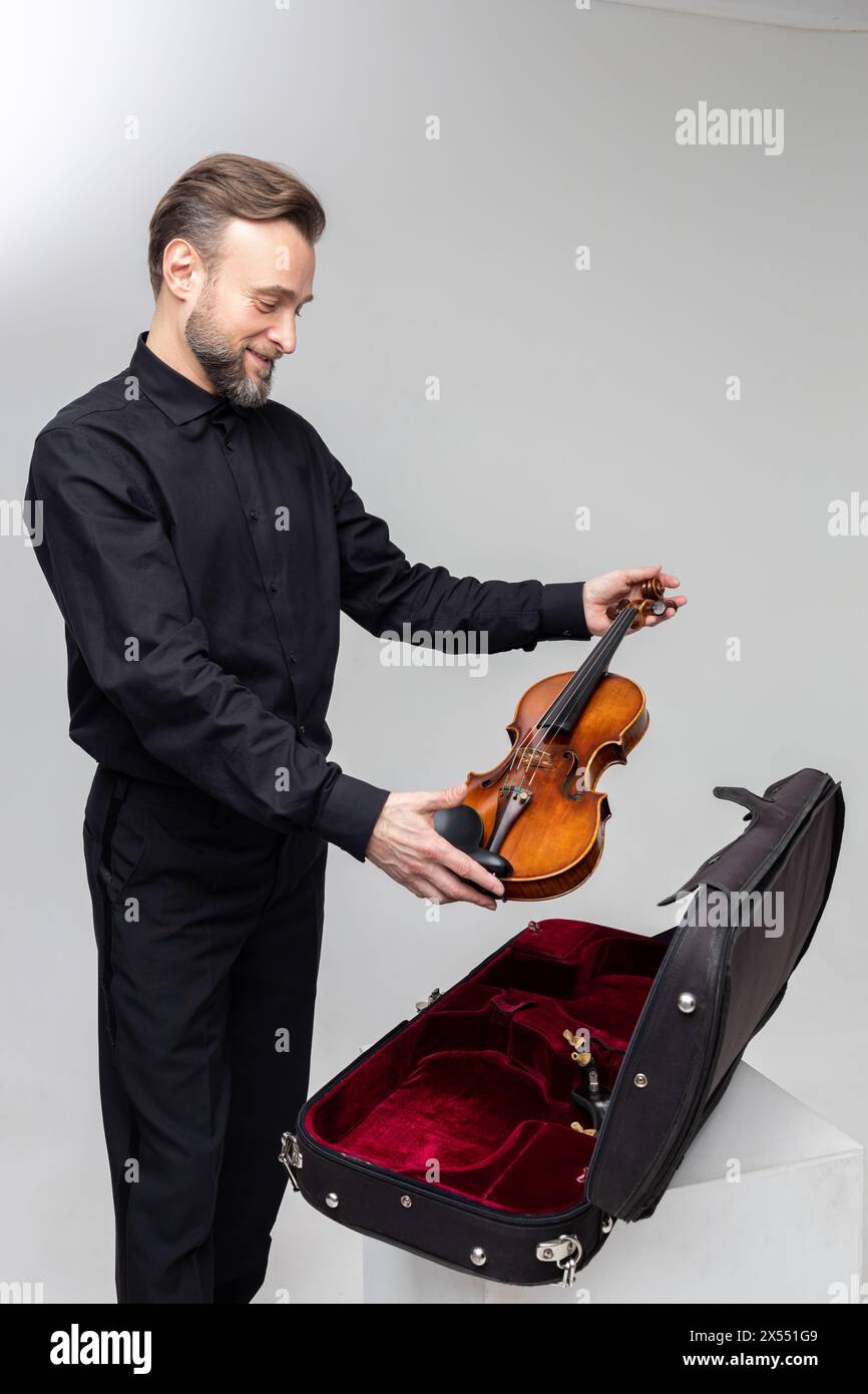 Bearded man artist packing musical instrument in violin case Stock ...