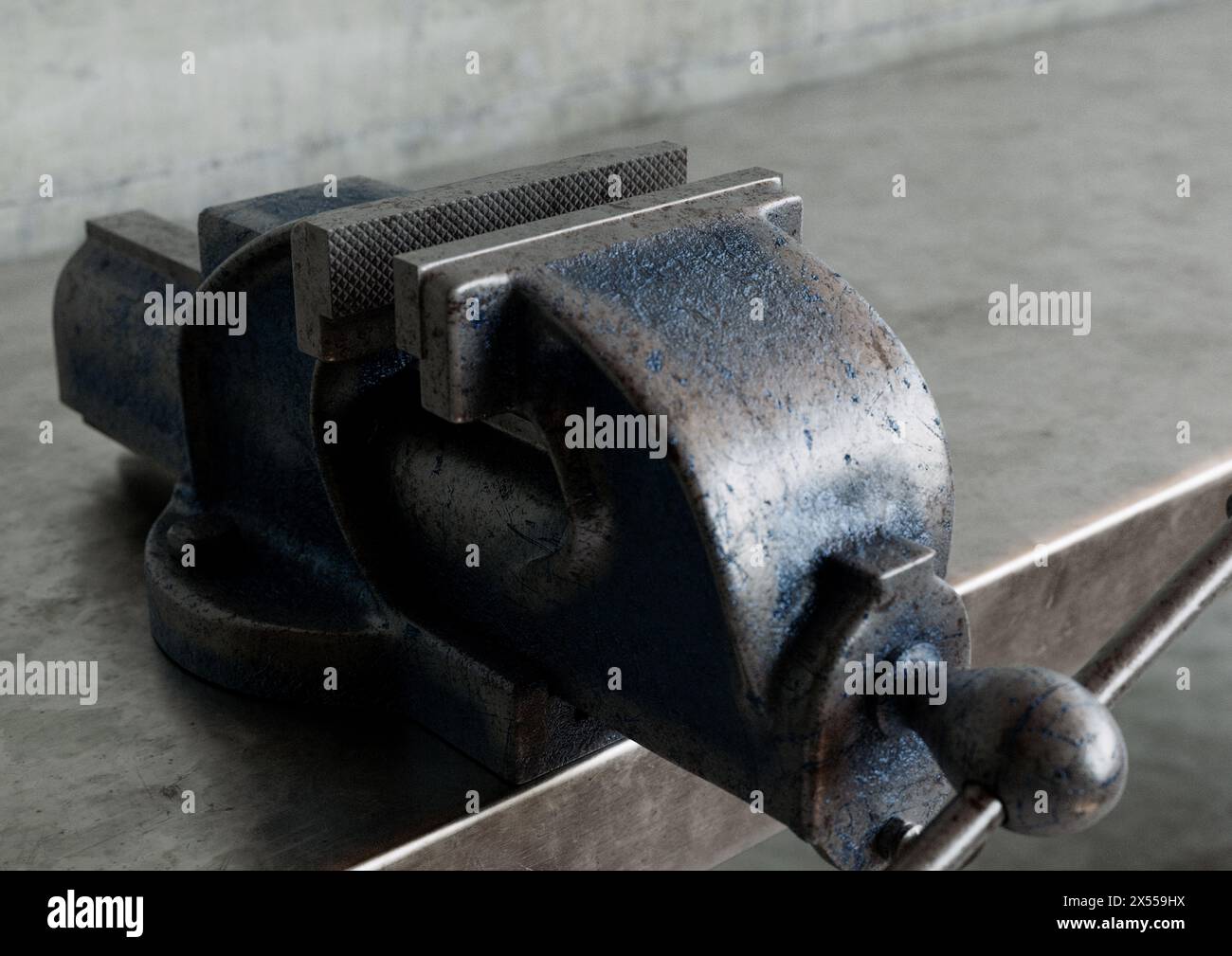 An industrial cast iron bench vice grip mounted on a metal workbench ...