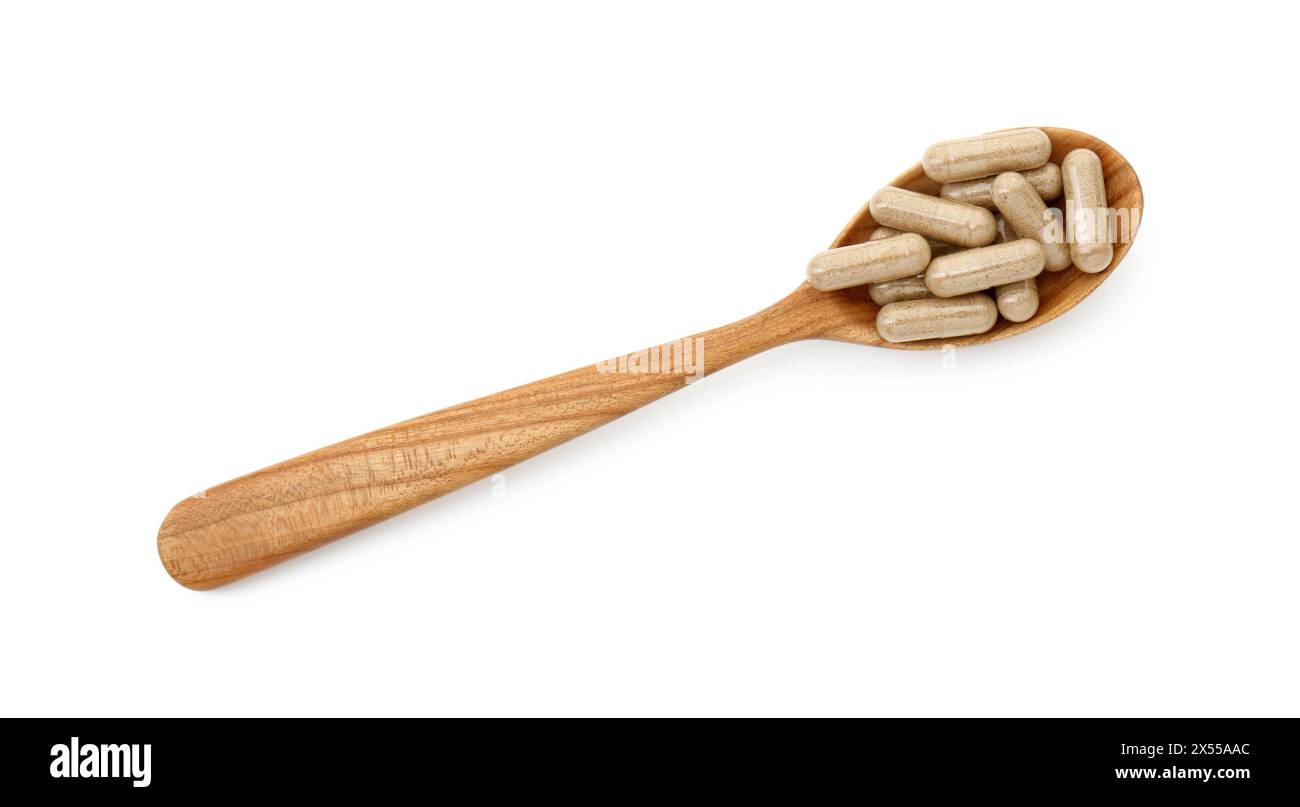 Vitamin capsules in wooden spoon isolated on white, top view. Health ...