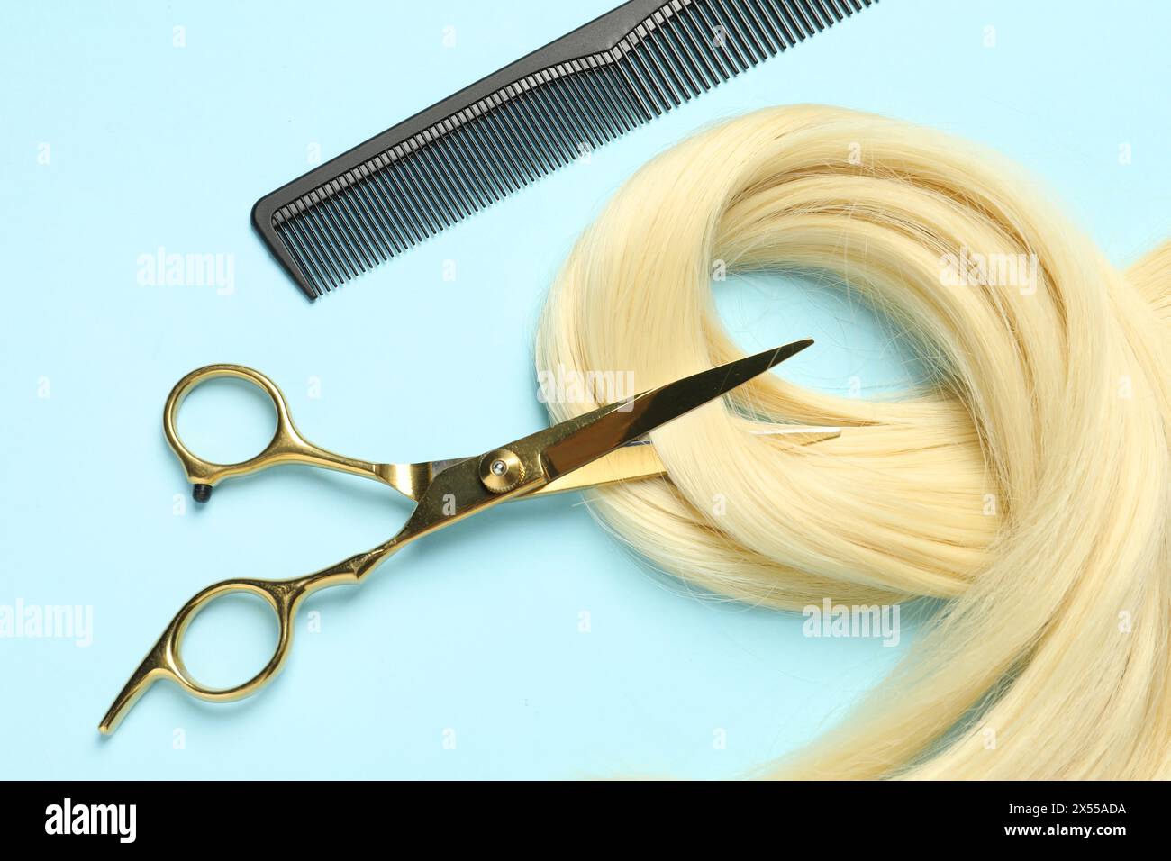 Professional hairdresser scissors and comb with blonde hair strand on ...