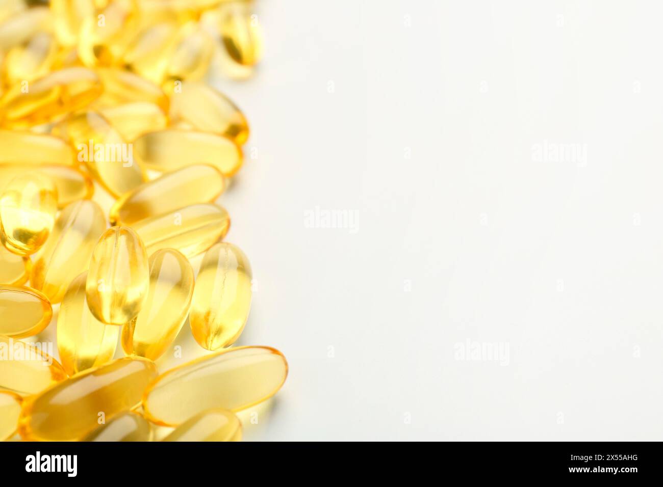 Yellow vitamin capsules on white background, closeup. Space for text ...