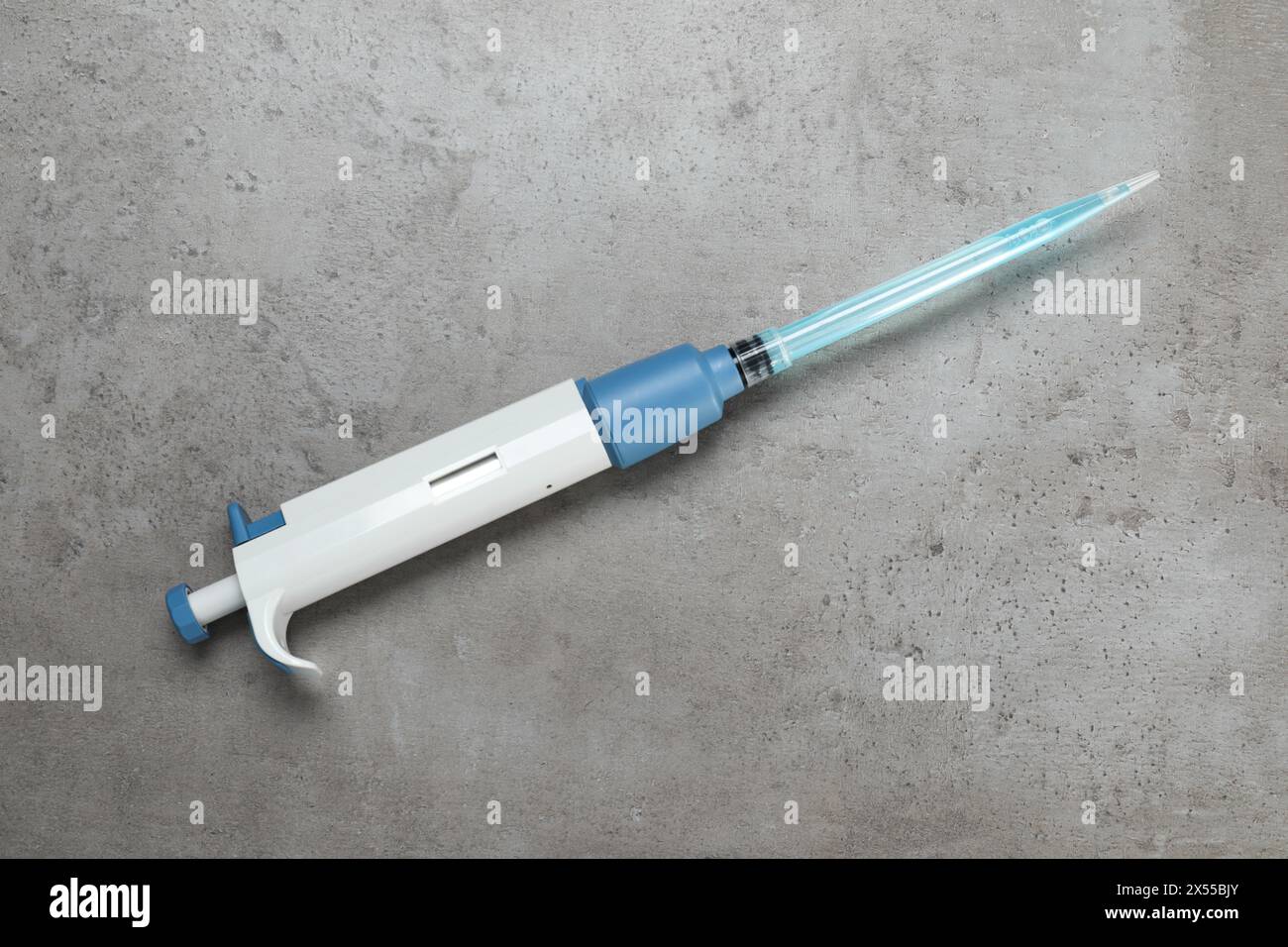 Laboratory analysis. Micropipette with liquid on grey table, top view ...