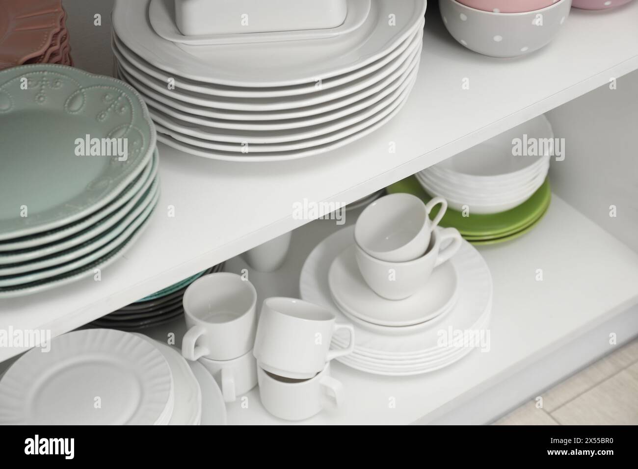 Clean plates, bowls and cups on shelves in cabinet indoors Stock Photo ...