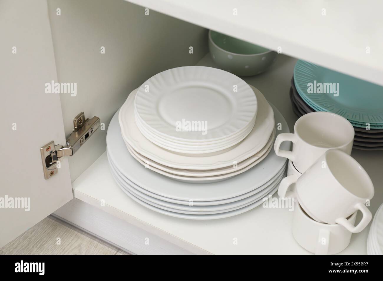 Clean plates and cups on shelf in cabinet indoors Stock Photo - Alamy