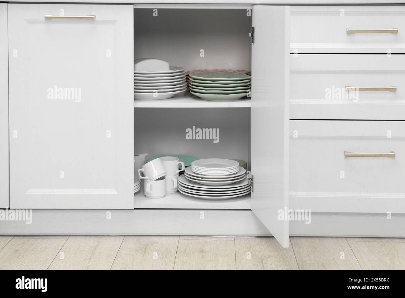 Clean plates and other crockery on shelves in cabinet indoors Stock ...