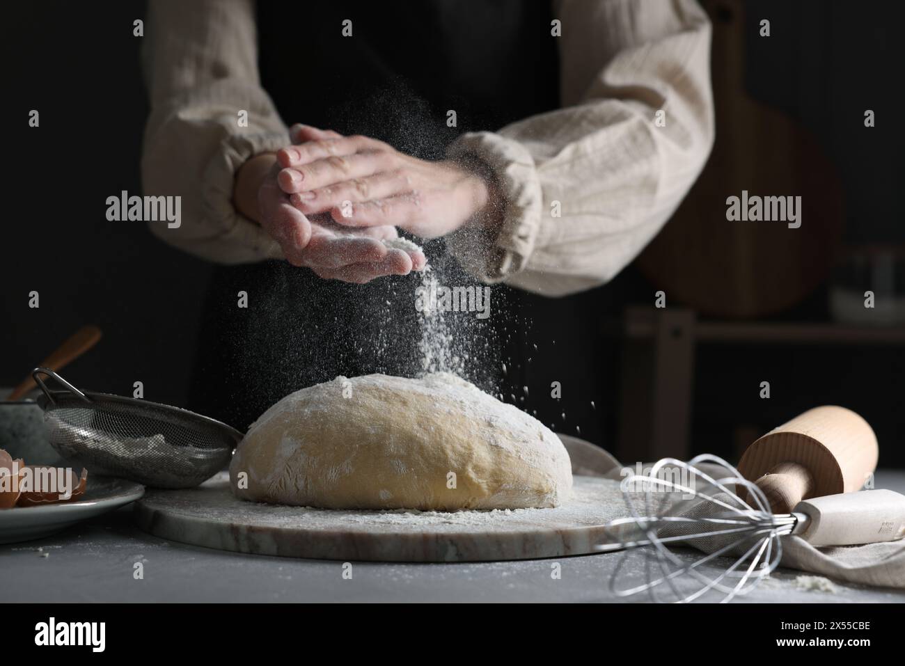 Making dough. Woman adding flour at grey table, closeup Stock Photo - Alamy